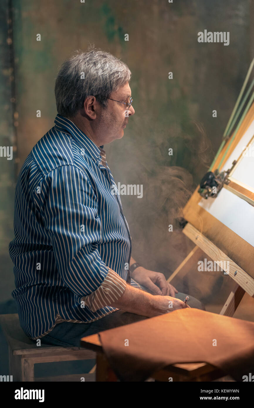 The mature creative engineer working with project on drawing board ...