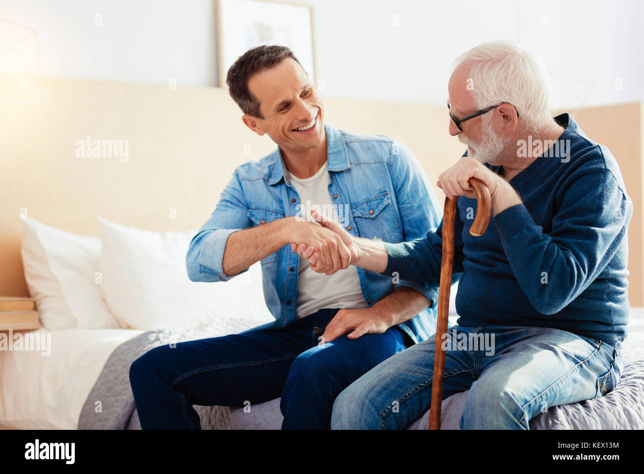 Cheerful visitor shaking hands with old man Stock Photo - Alamy
