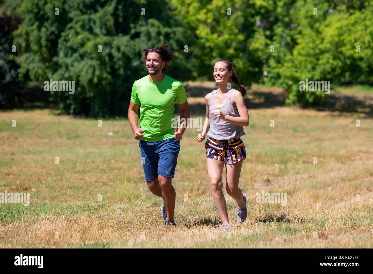 Healthy, fit and sportive couple running in park at summer morning ...