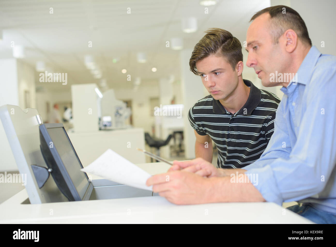 Two men looking at paperwork and equipment Stock Photo - Alamy