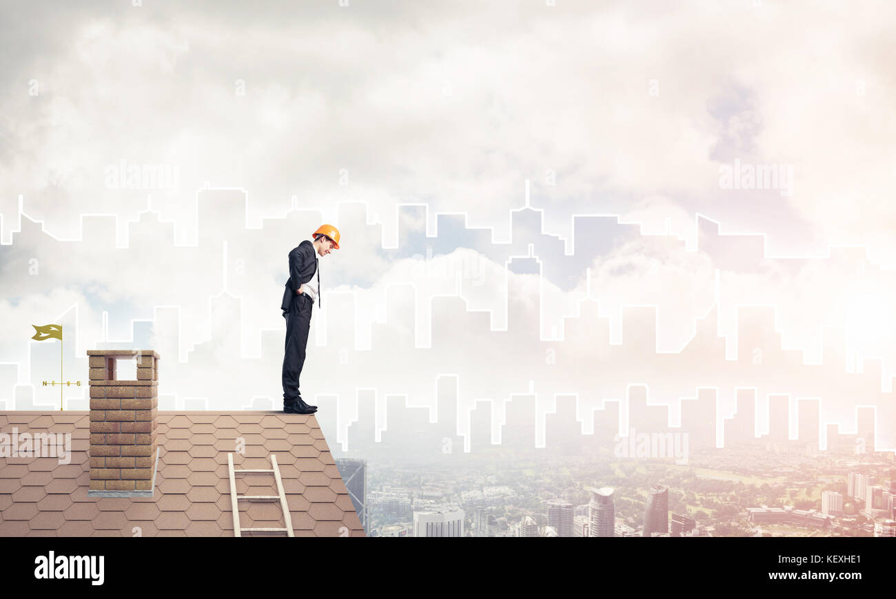 Engineer man standing on roof and looking down. Mixed media Stock Photo ...