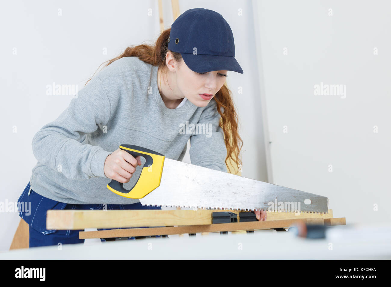 young woman using a hand saw in a woodshop Stock Photo - Alamy