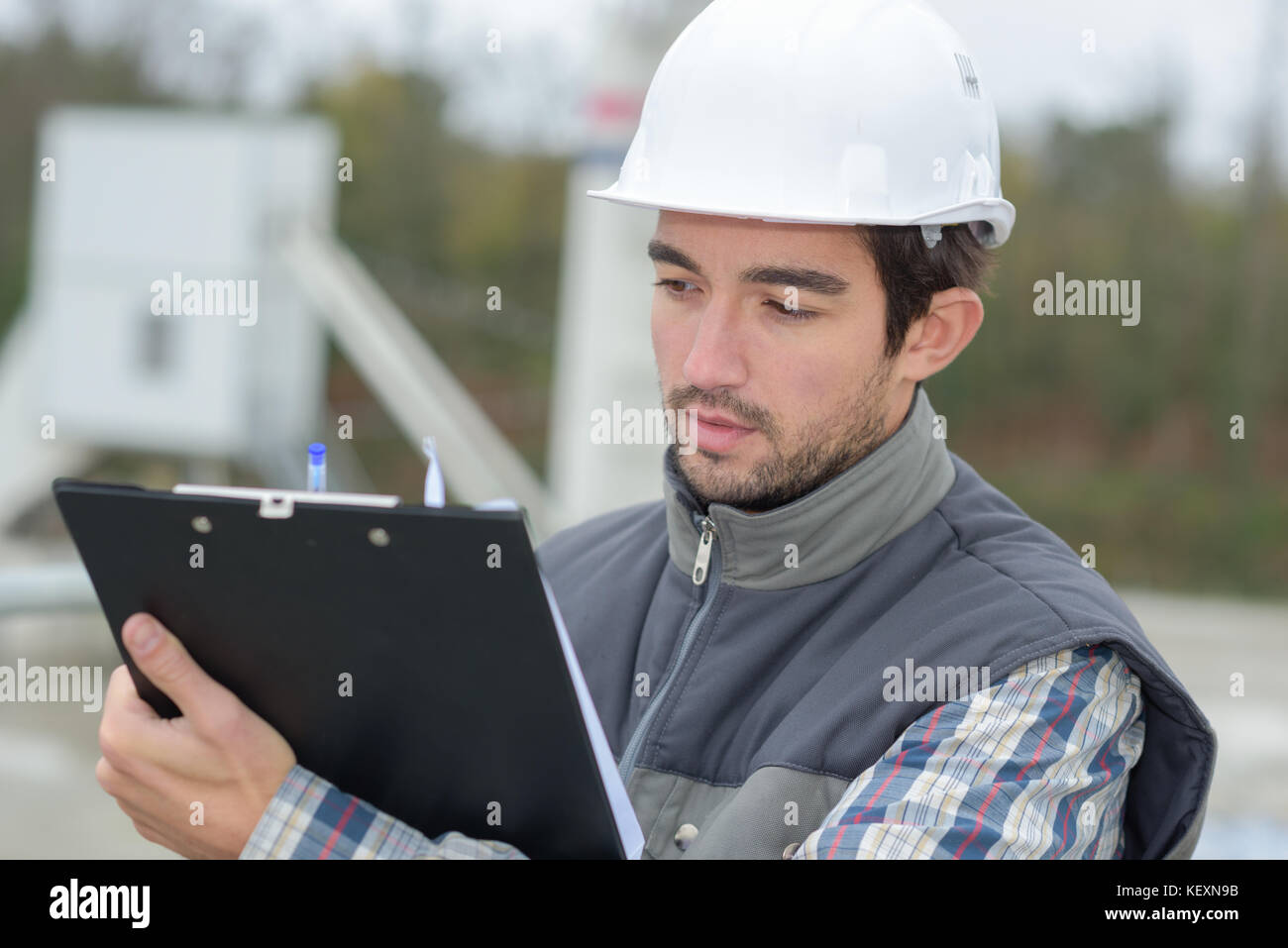 male architect with blueprints reading clipboard outdoors Stock Photo ...