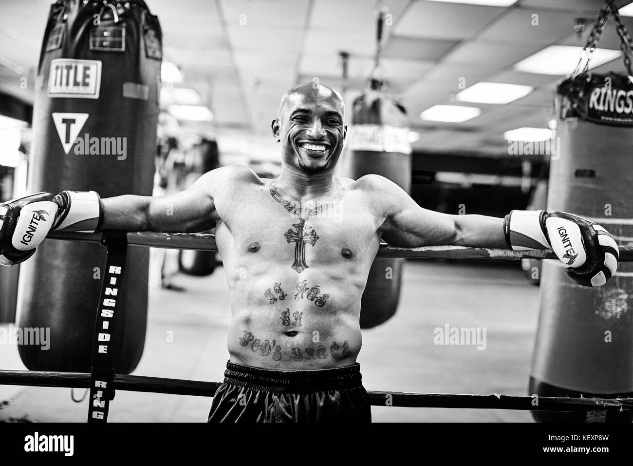 Portrait of male boxer leaning on boxing ring ropes and smiling ...