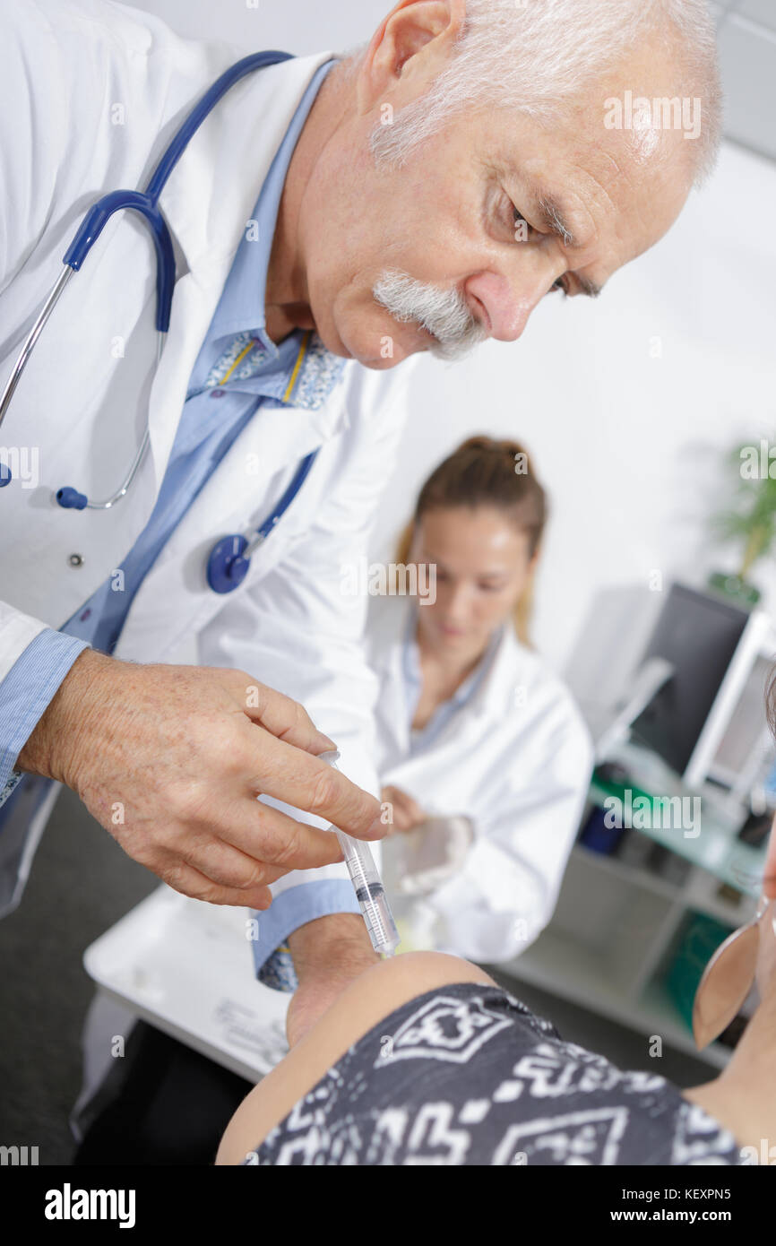 senior doctor giving an injection to a patient Stock Photo - Alamy