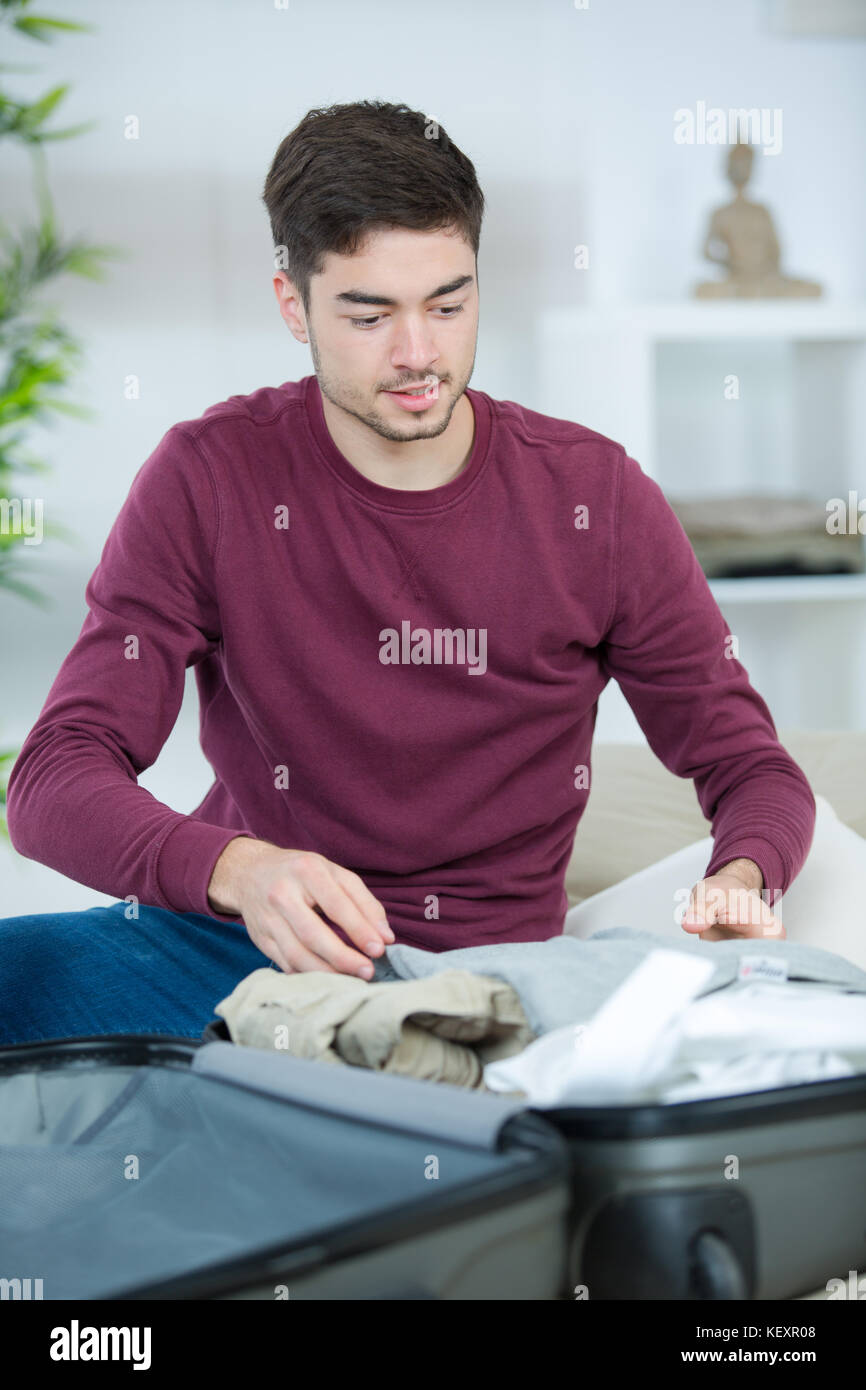 young man packing suitcase at home Stock Photo - Alamy