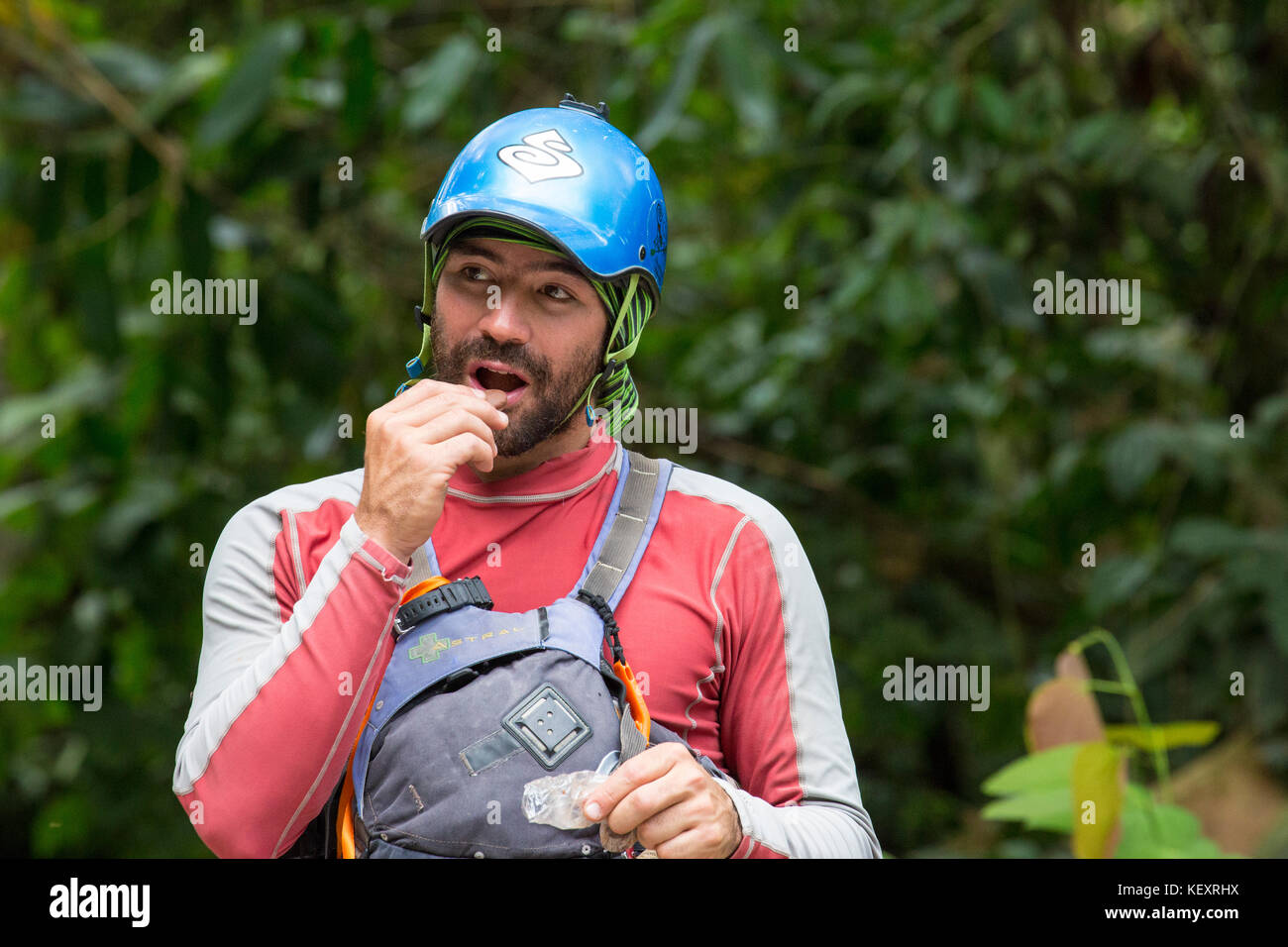 Photograph of man preparing for stand-up paddleboarding on jungle river ...