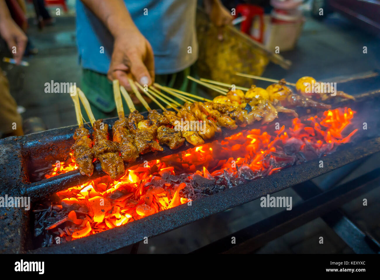 Street barbecue with meat skewers sizzling, very hot fire burning and ...