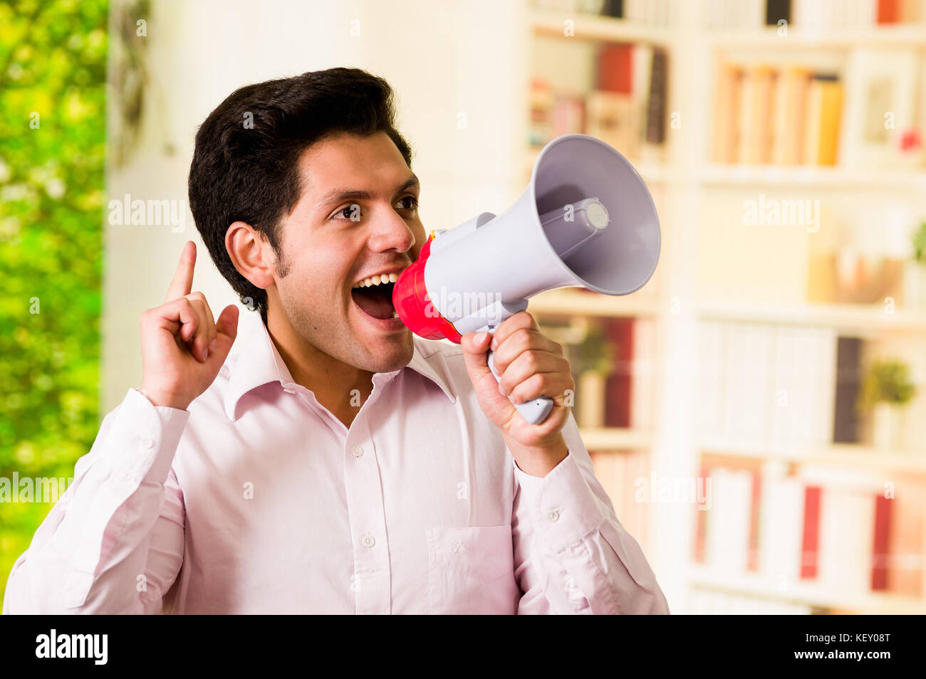 Close up of a handsome man screaming with a megaphone in a blurred ...