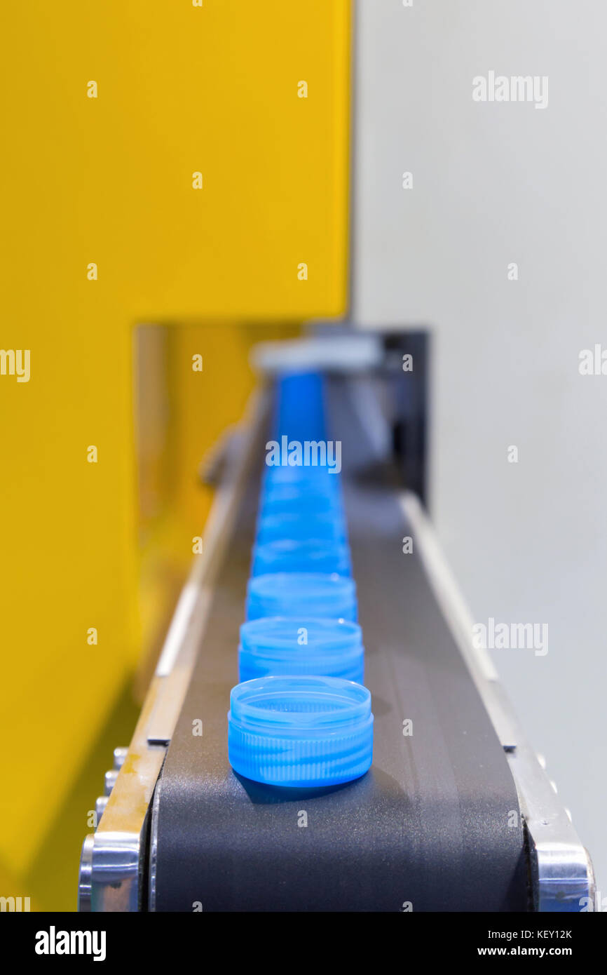 blue plastic bottle caps in production line on machine conveyor at ...
