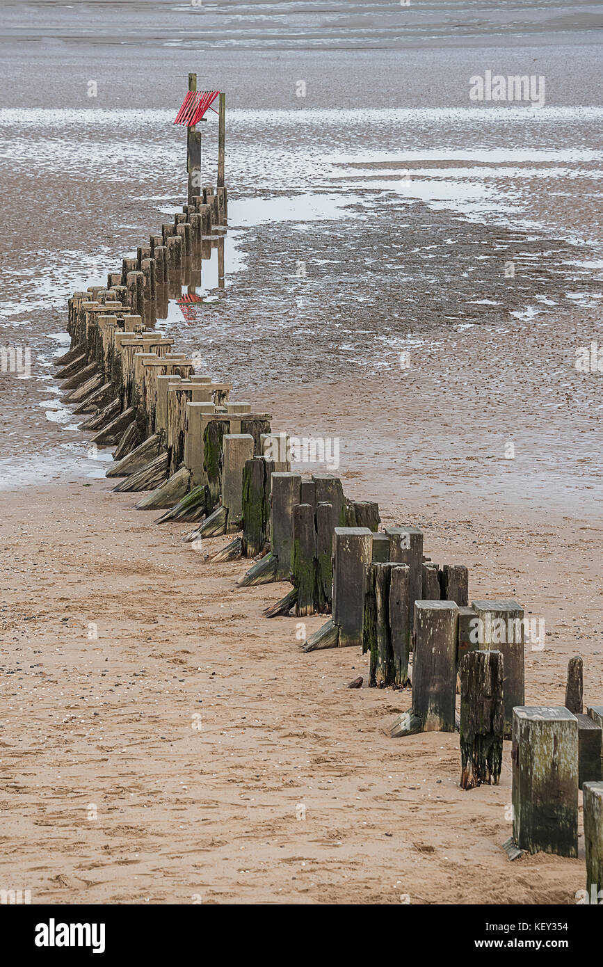A close upright photograph of wooden groynes on a deserted beach Stock ...