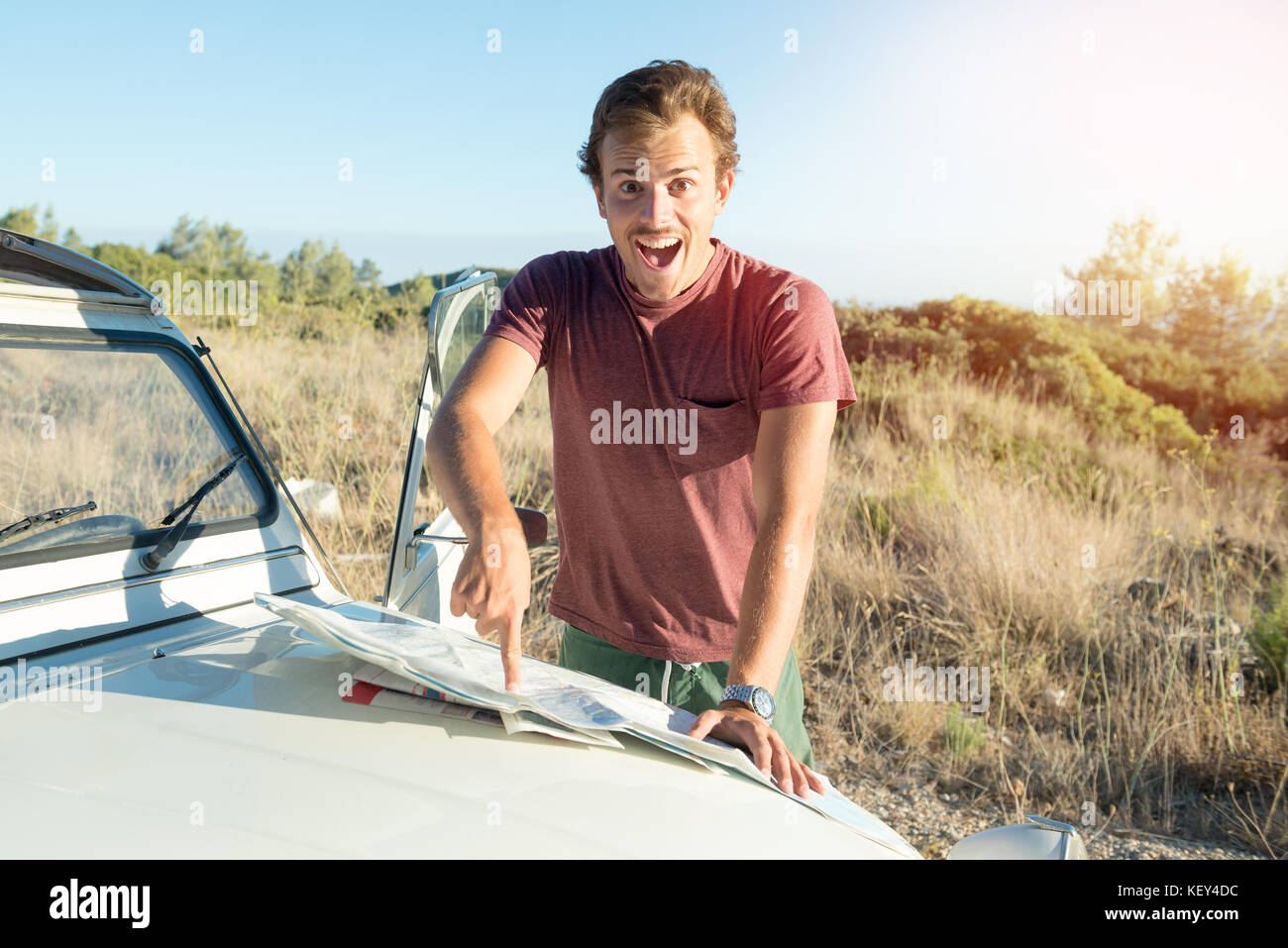 Vintage style image of a man looking at a map over a car in countryside ...