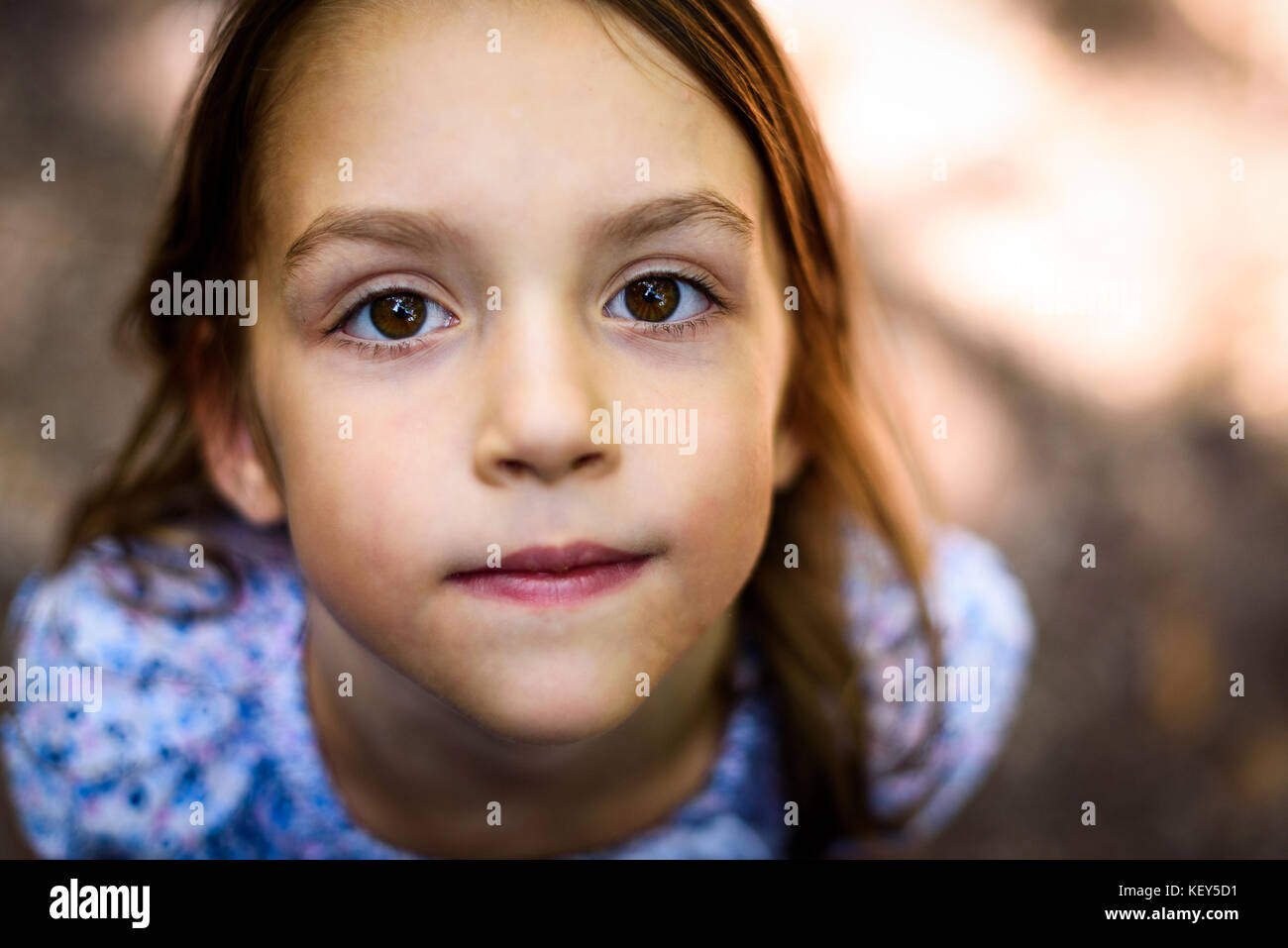 Portrait of little girl looking up at the parent outdoors. A child is ...