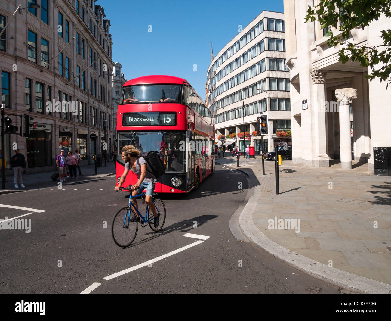 A London bus is preceded by a cyclist in this street scene. The bus is ...