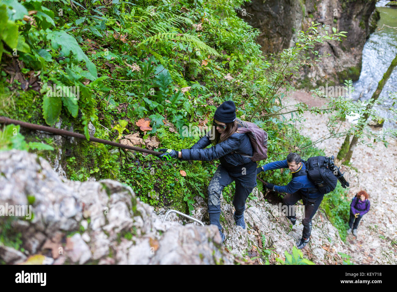 Group of hikers climbing on safety cable on mountain wall Stock Photo ...