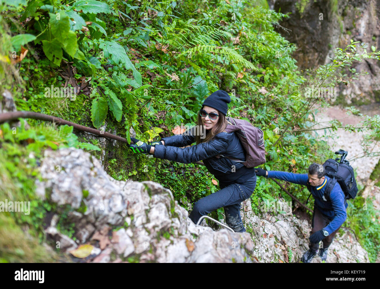 Group of hikers climbing on safety cable on mountain wall Stock Photo ...