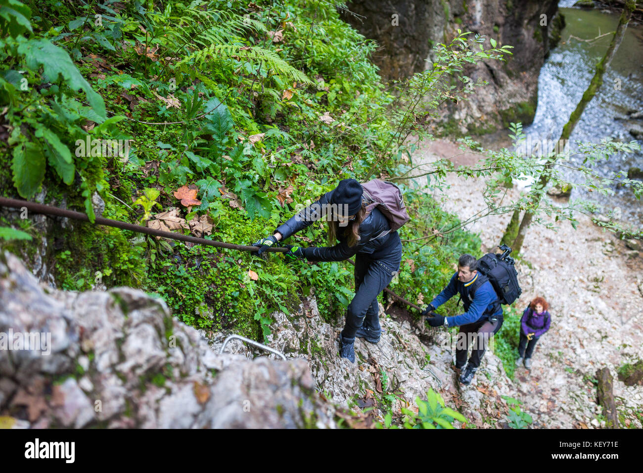 Group of hikers climbing on safety cable on mountain wall Stock Photo ...