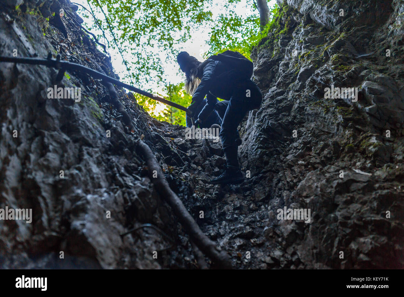 Group of hikers climbing on safety cable on mountain wall Stock Photo ...