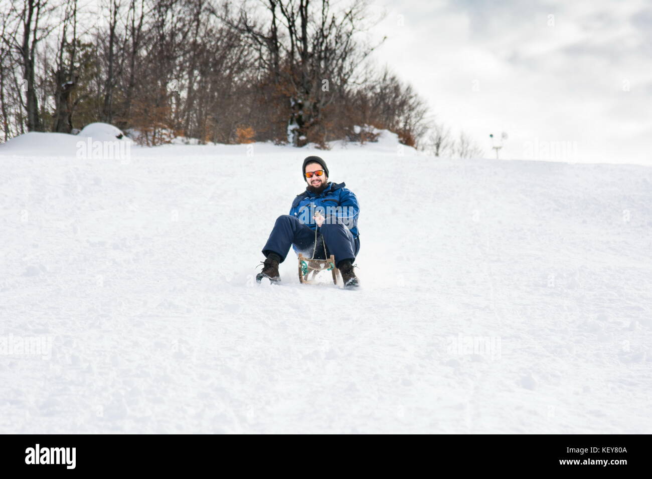 Bearded man sleighing down hill on the snow Stock Photo - Alamy
