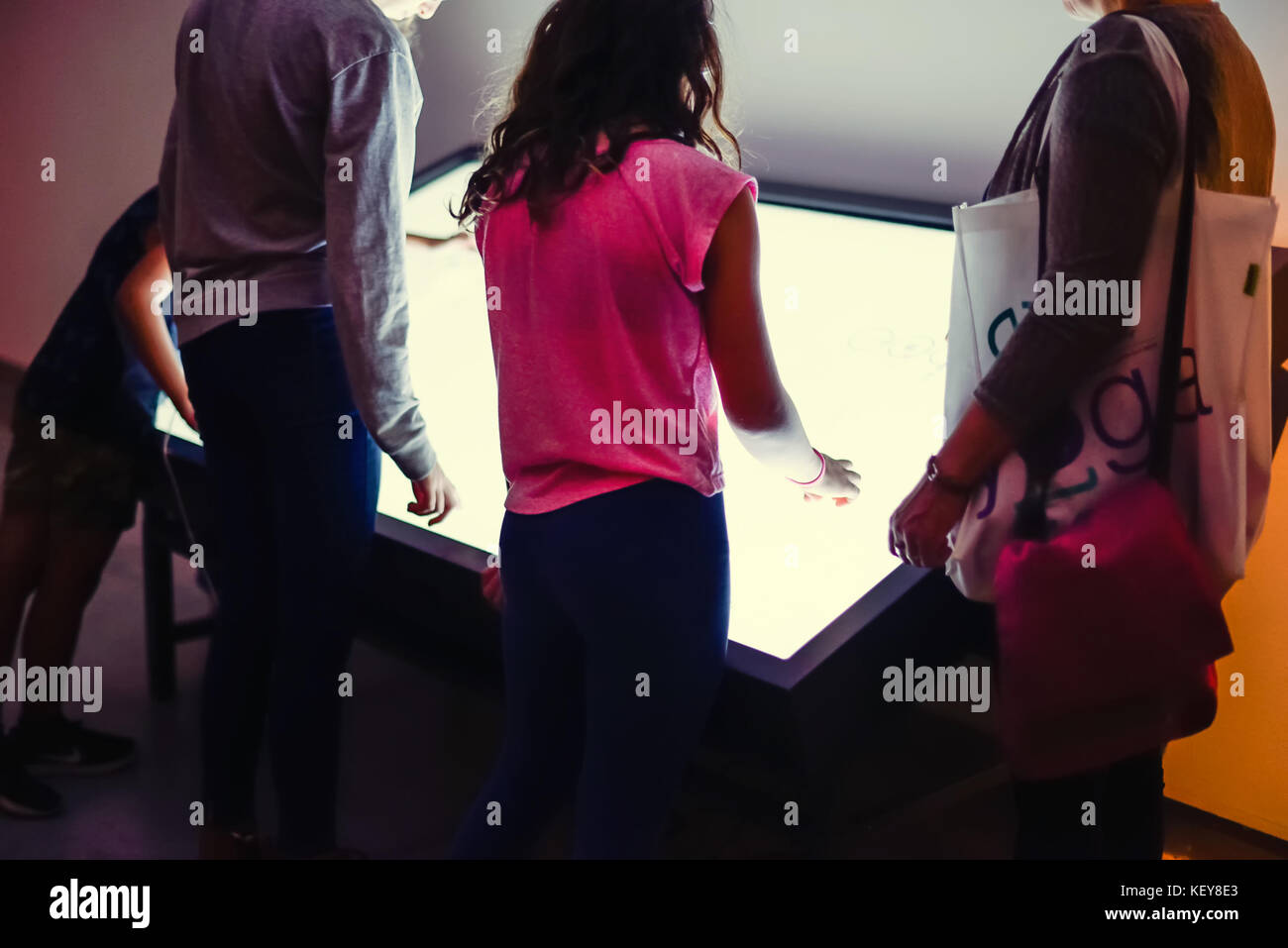 Children and adults using interactive touch screen in a museum. Modern ...