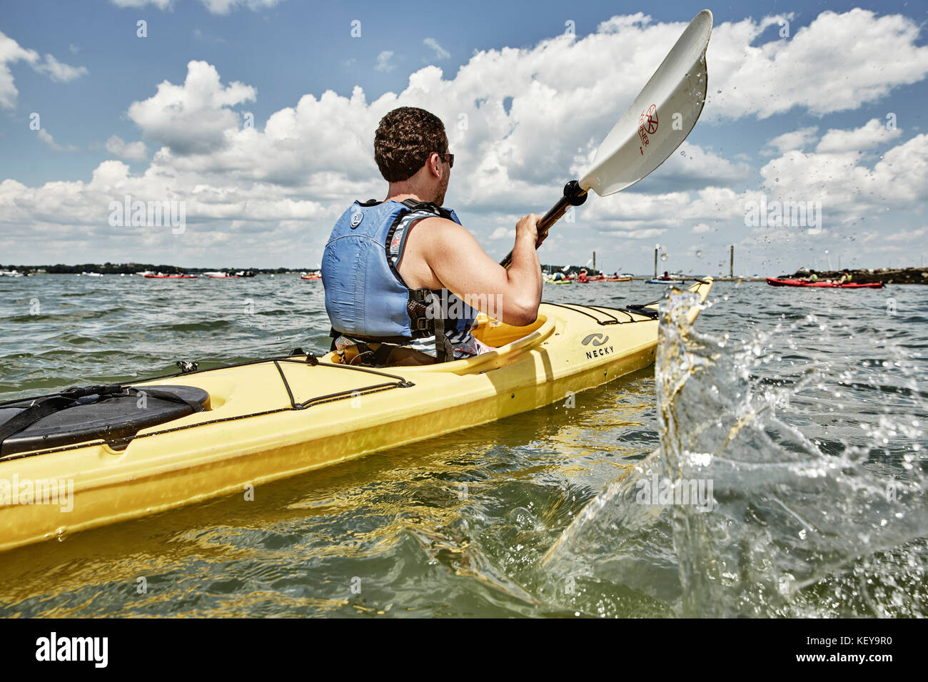 Rear view of man kayaking against white clouds, Portland, Maine, USA ...