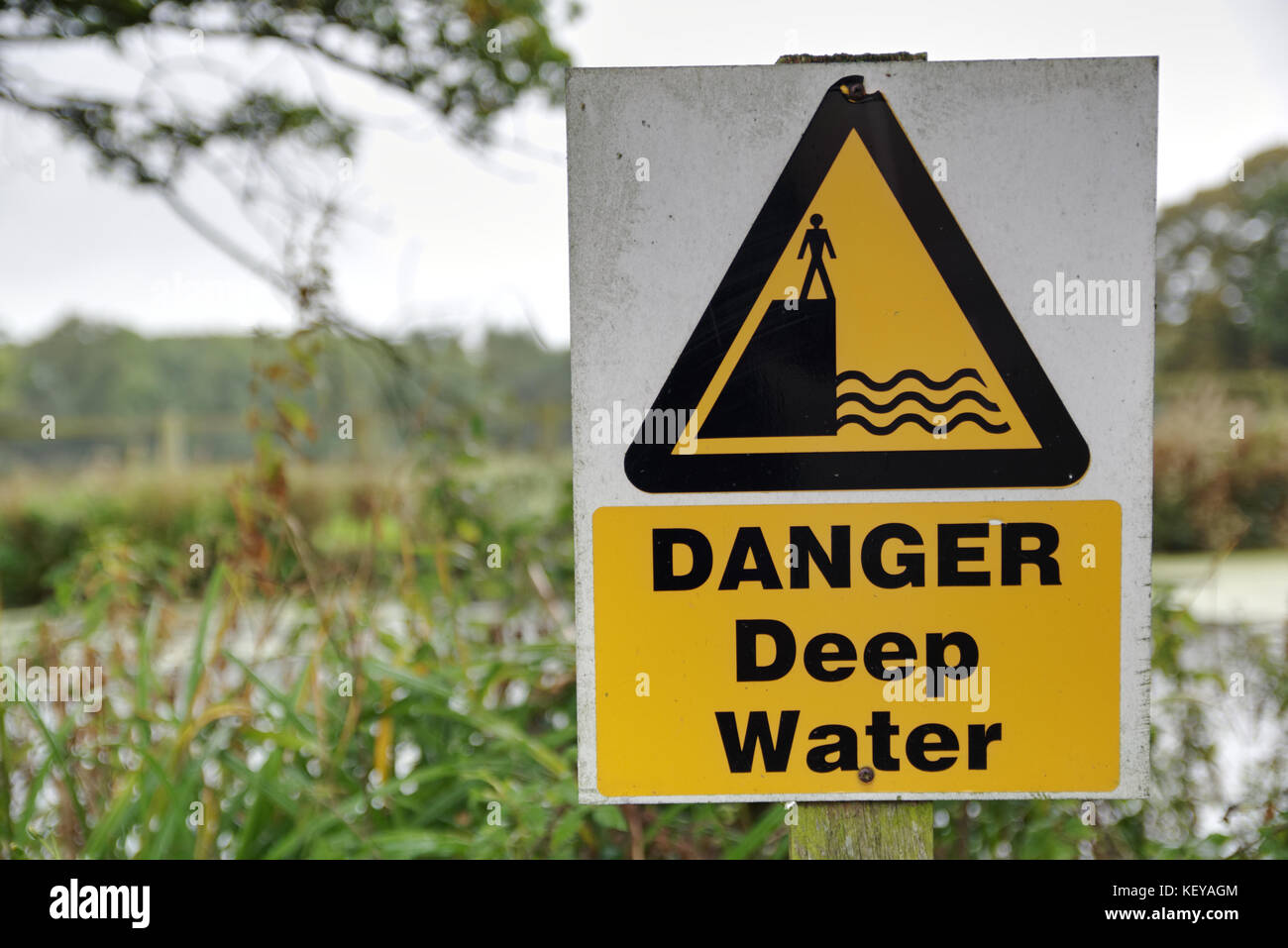 Old yellow and black DANGER Deep Water sign at the lake Stock Photo - Alamy