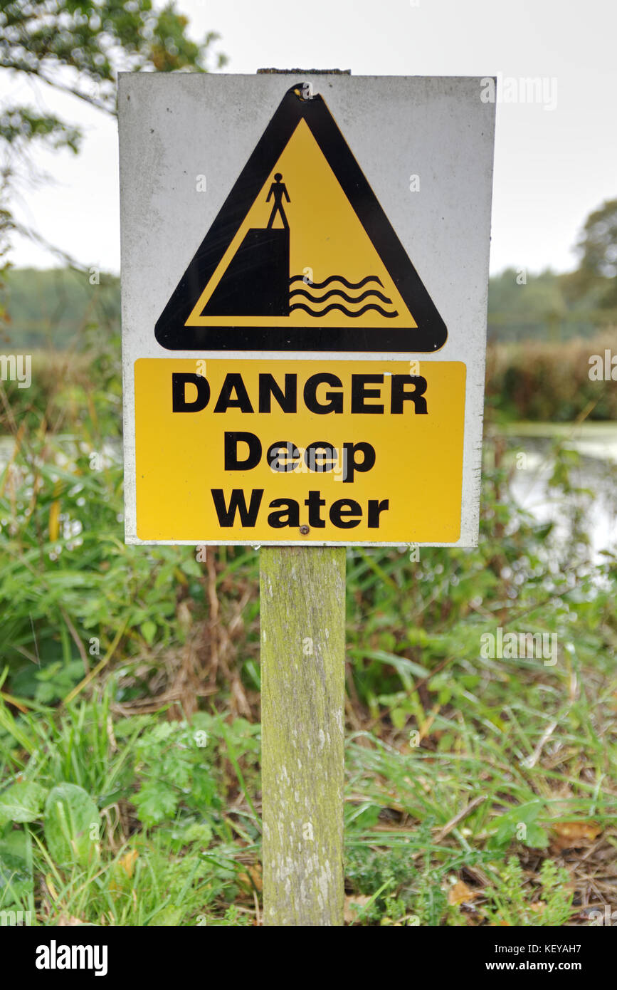 Old yellow and black DANGER Deep Water sign at the lake Stock Photo - Alamy