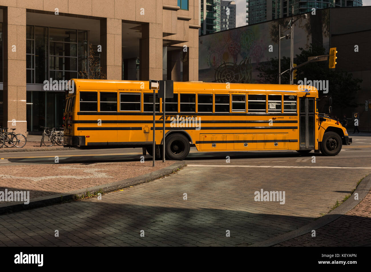 A yellow old fashioned school bus driving via streets of downtown in ...
