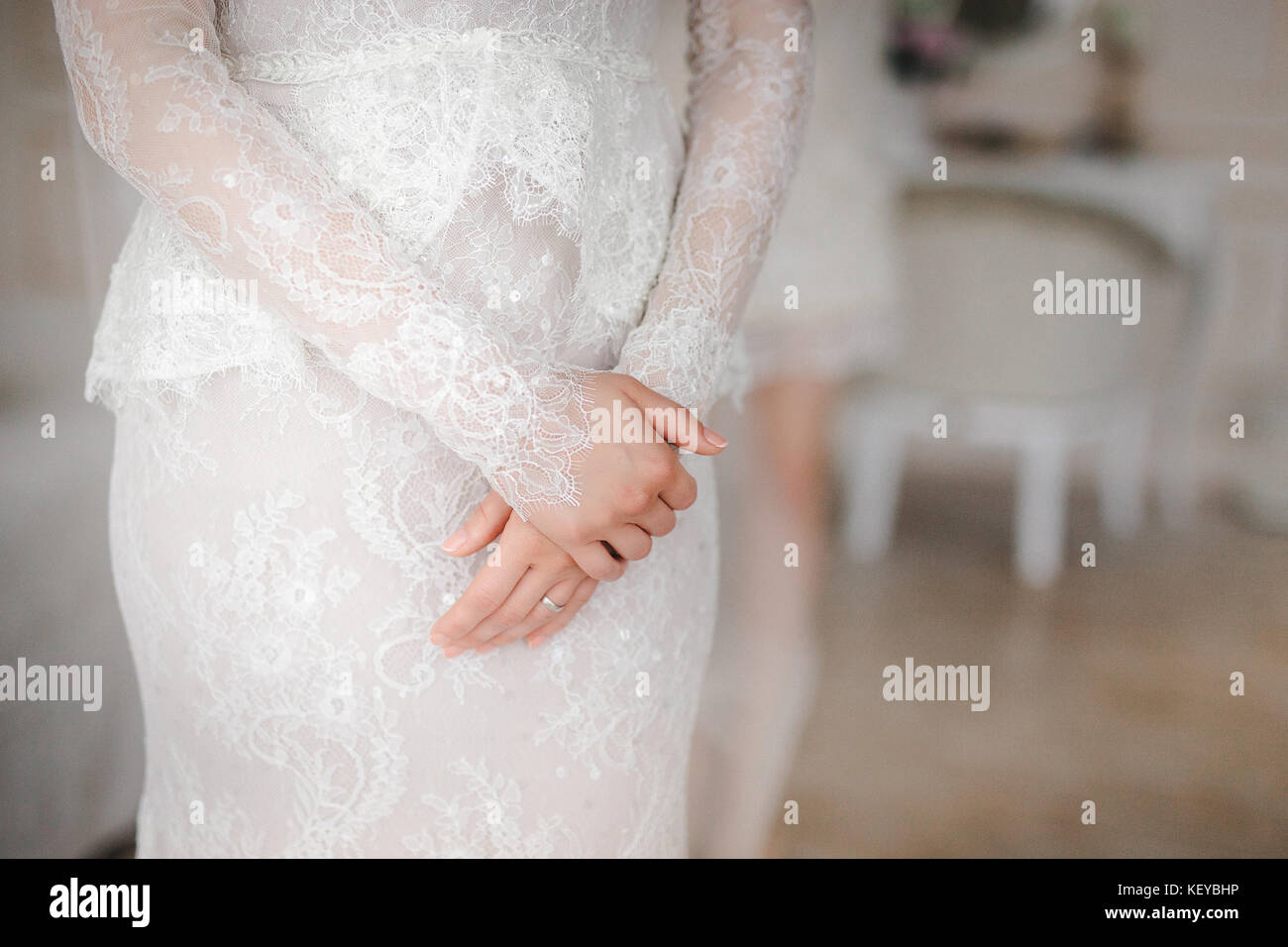 Bridesmaid preparing bride for the wedding day, helping fasten her ...