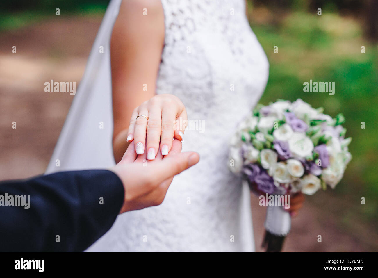 The groom holds the hand of the bride. Wedding details Stock Photo - Alamy