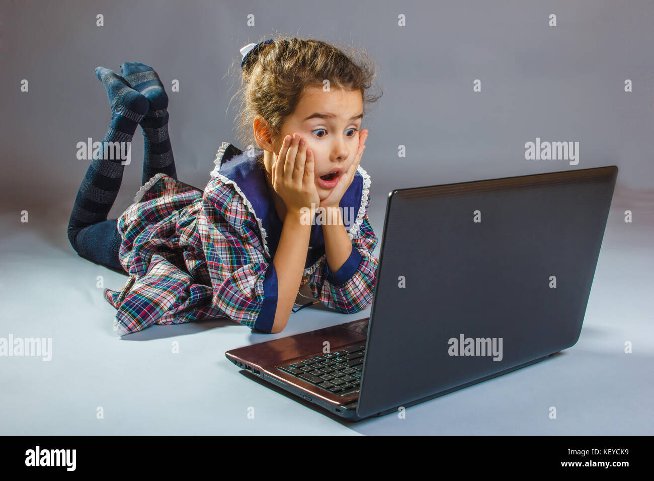 baby girl surprised looking computer on a gray background Stock Photo ...