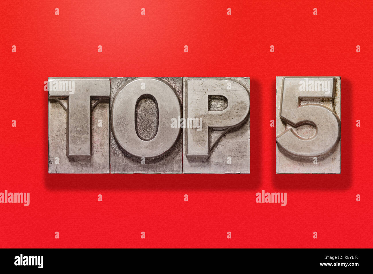 top five metallic letterpress numbers assembled on red textured ...