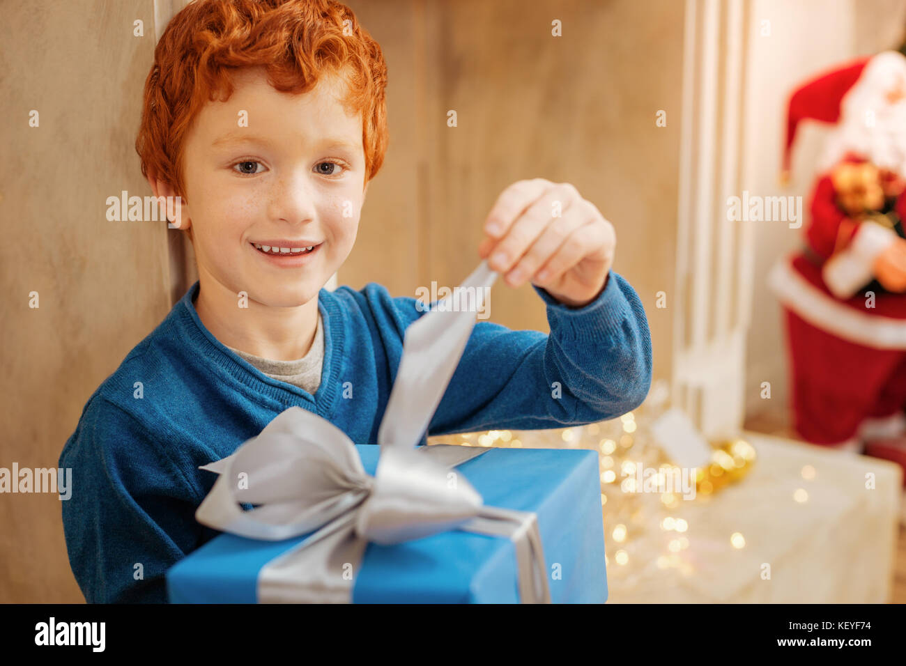 Adorable kid smiling into camera while opening his present Stock Photo ...