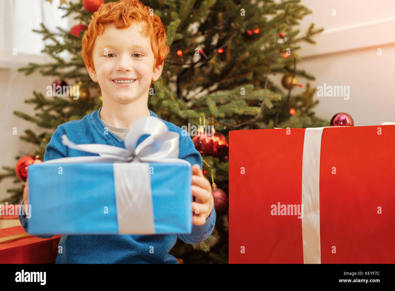 Thoughtful little boy handing over christmas present Stock Photo - Alamy