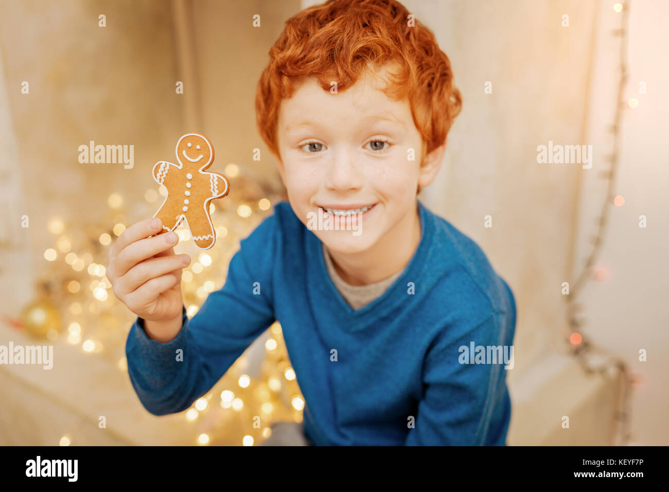 Excited curly haired kid showing gingerbread man Stock Photo - Alamy