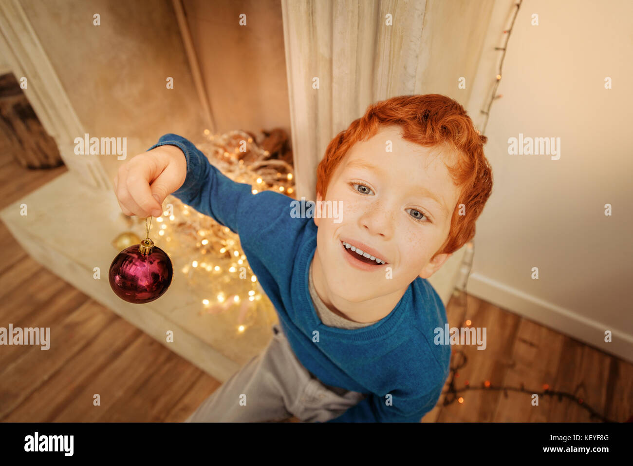 Charming ginger child smiling while decorating house for christmas ...