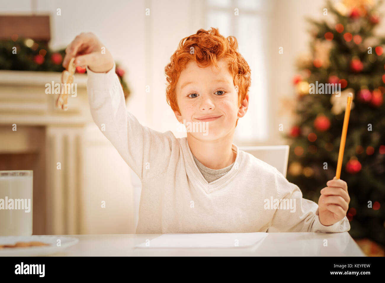 Charming redhead boy lifting gingerbread man and smiling Stock Photo ...