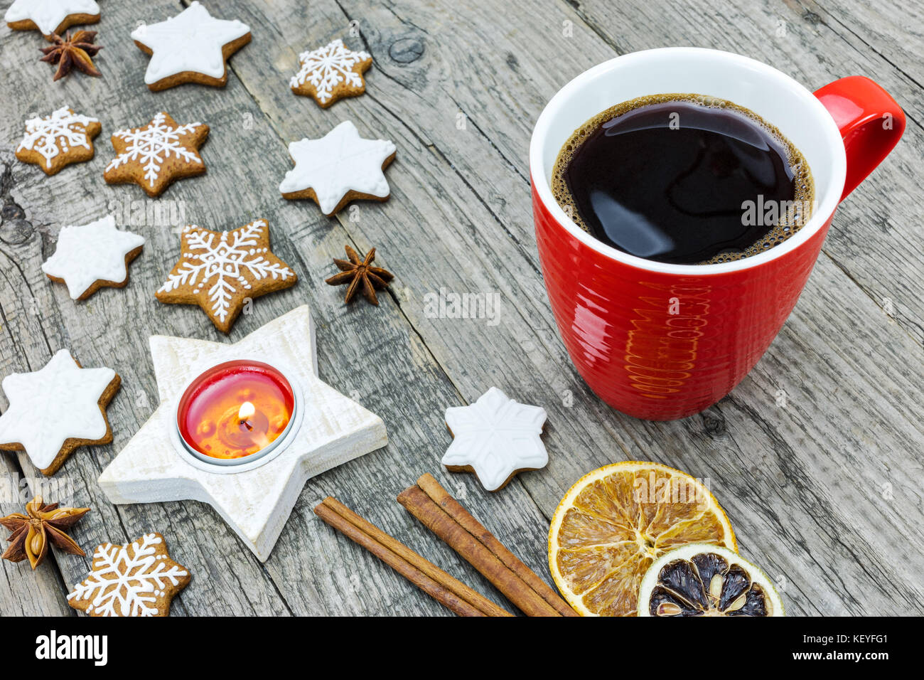 iced star cookies with lit candle, cinnamon, slices of orange and cup ...