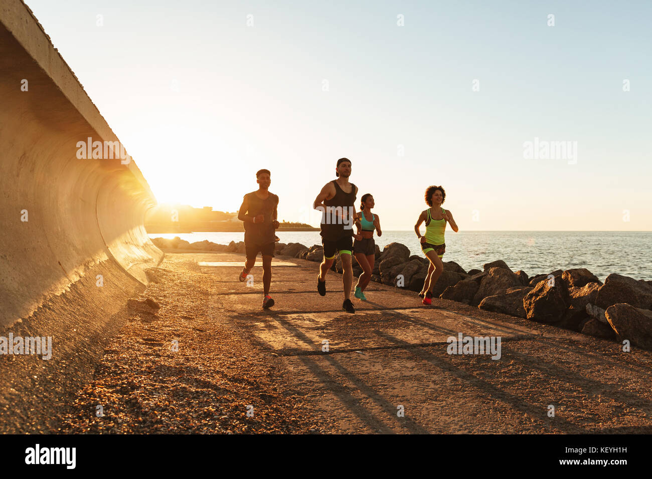Full length image of sports people running outdoors at the beach Stock ...