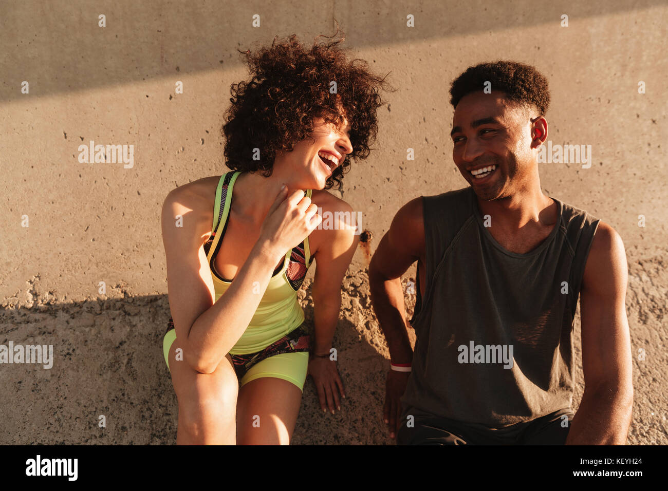 Two happy sports people sitting on pier while having rest after ...