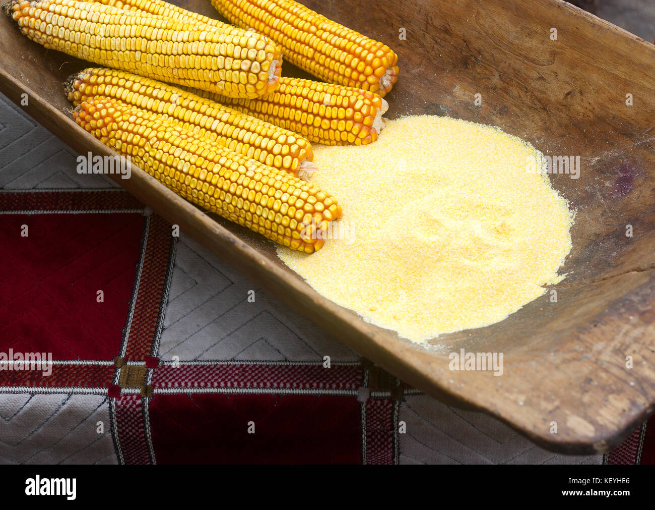 Corn cobs and corn flour in a wooden trough, presented at an ...