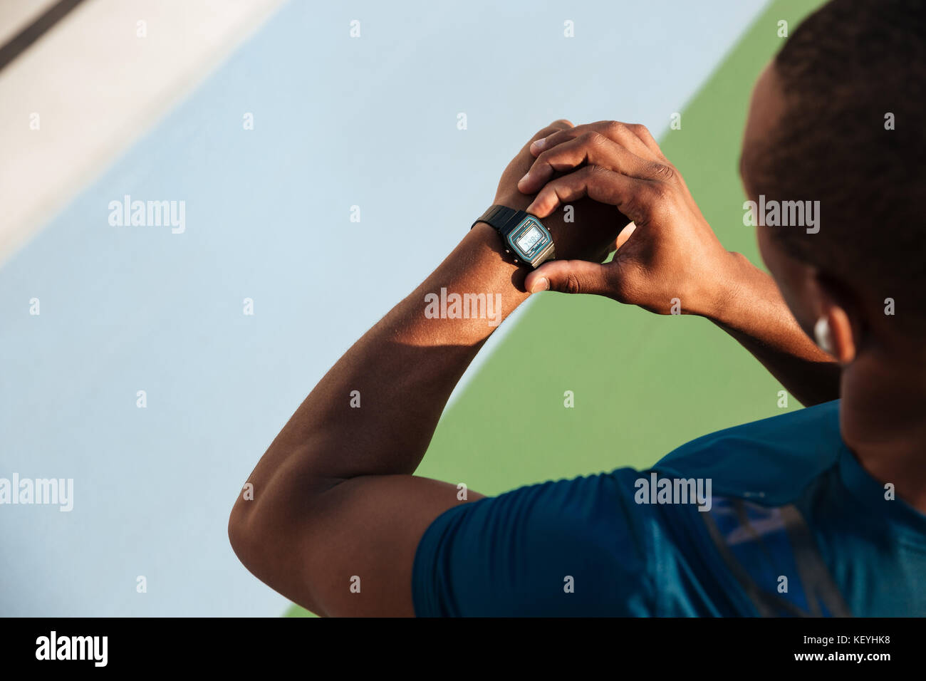 Top view close up of a fit african sportsman looking at his wrist watch ...