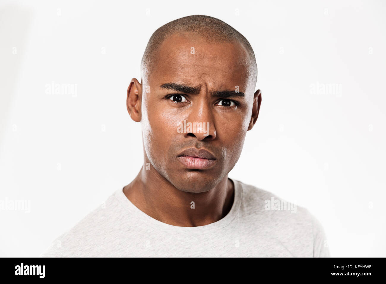 Photo of confused young african man standing isolated over white ...