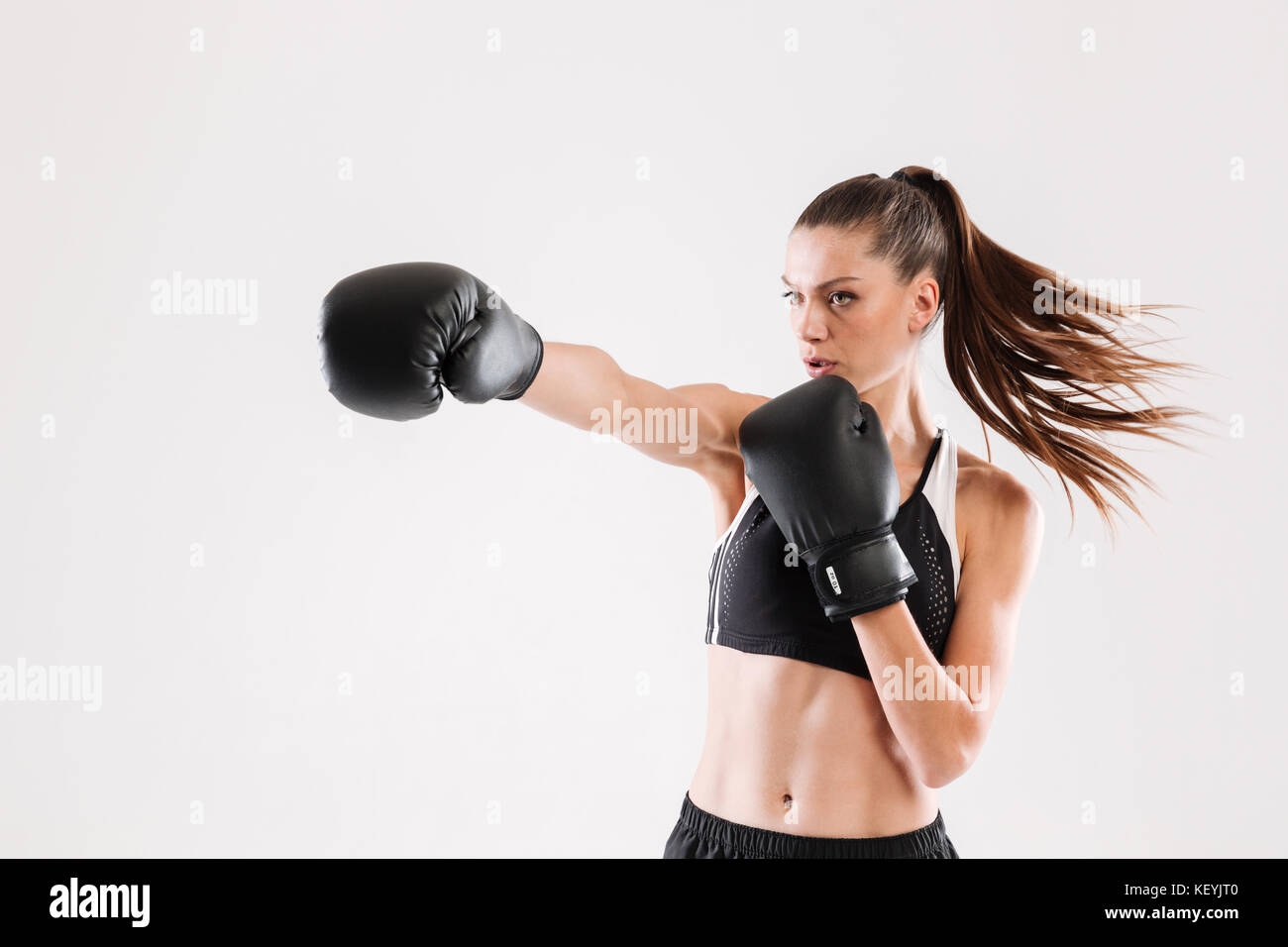 Portrait of a young motivated woman doing boxing lesson isolated over ...