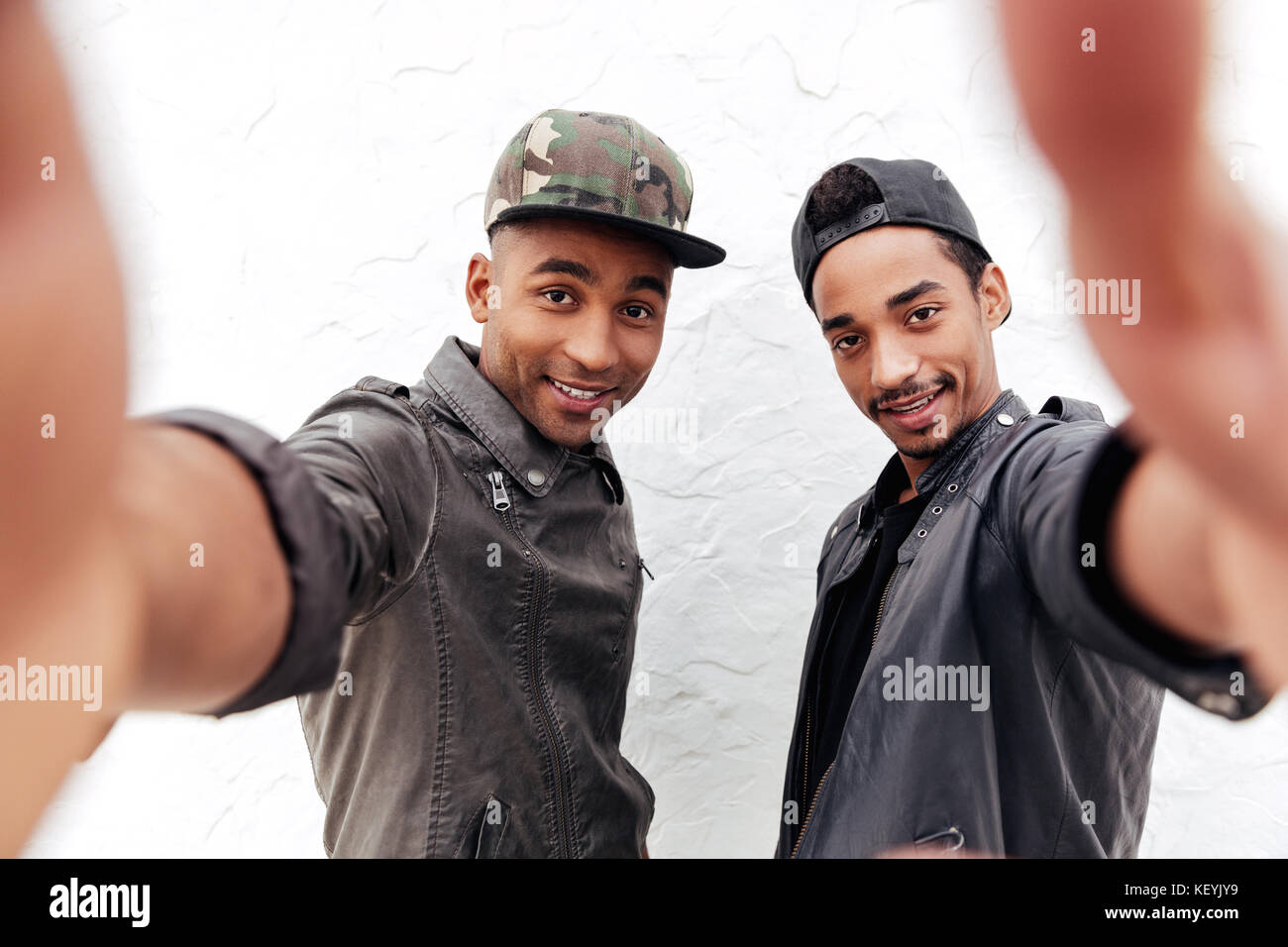 Photo of cheerful two young african men friends standing outdoors ...