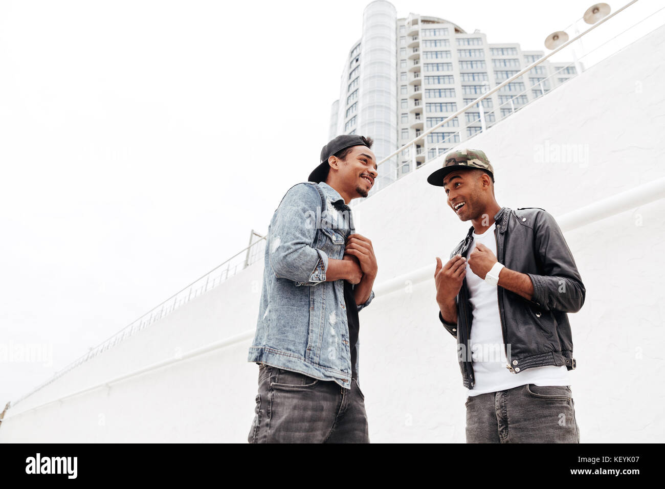 Two young african laughing men friends walking outdoors talking with ...
