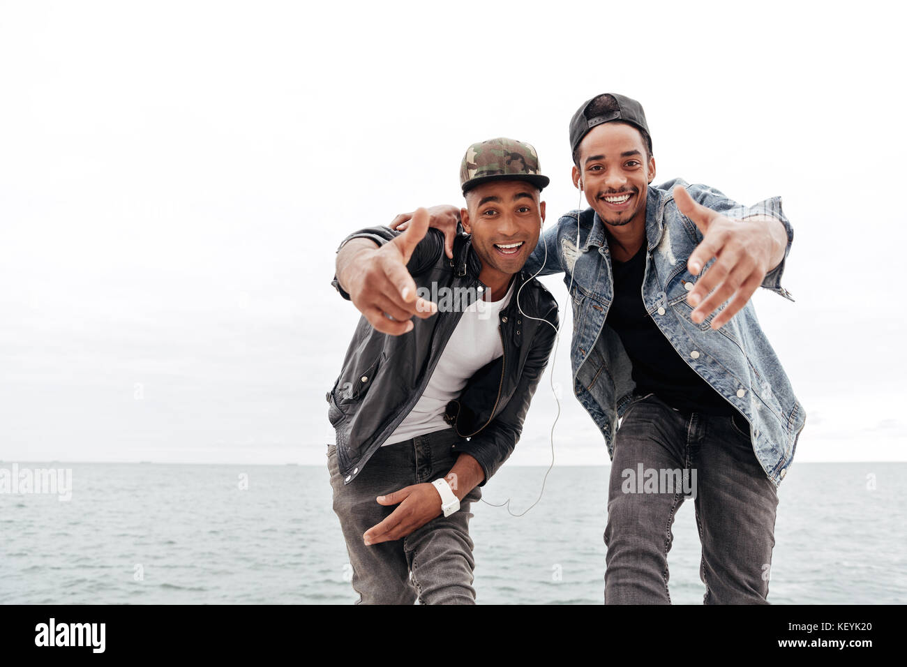 Photo of happy two young african men friends walking outdoors. Looking ...