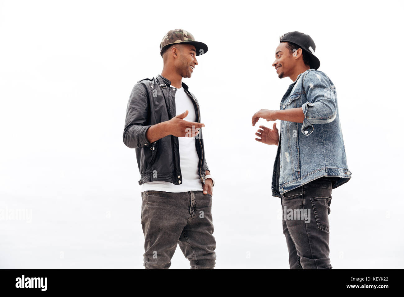 Photo of happy two young african men friends walking outdoors talking ...
