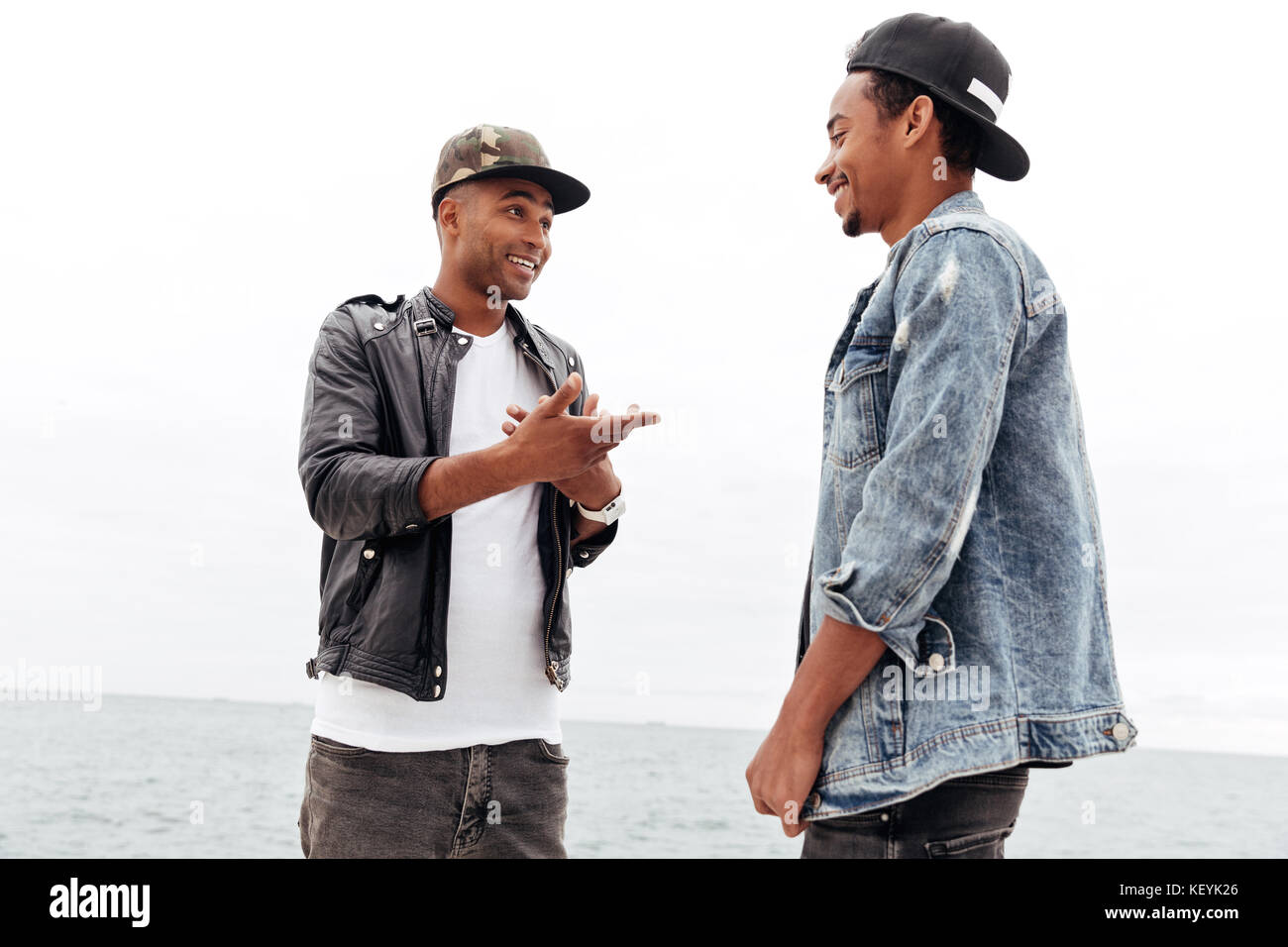 Photo of happy two young african men friends walking outdoors talking ...