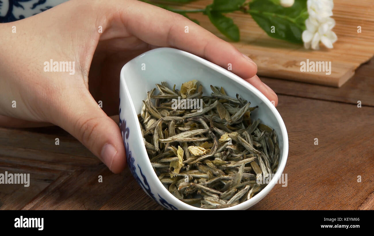 Glass teapot with blooming tea flower inside against wooden background ...